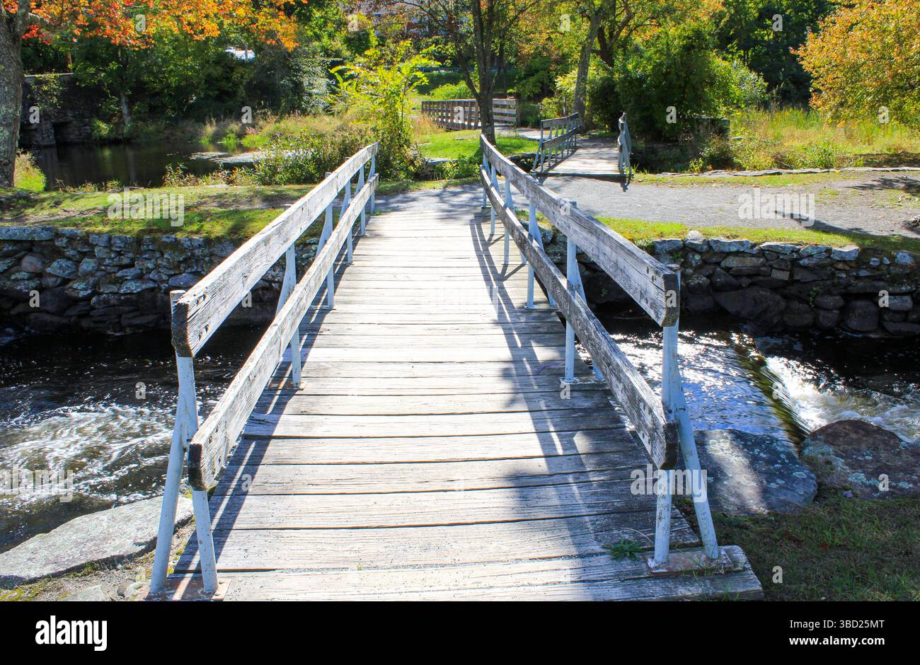 Autumn's breathtaking display: a footbridge spans flowing water ...