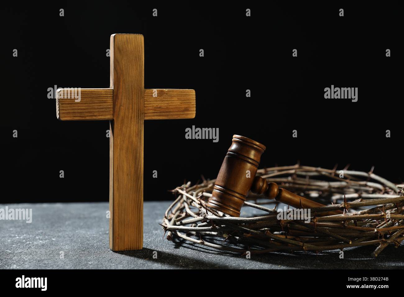 Crown of thorns, judge's gavel and wooden cross on dark textured ...