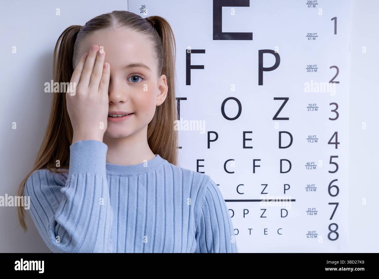 Cute caucasian girl on the Snellen vision test background at the ...