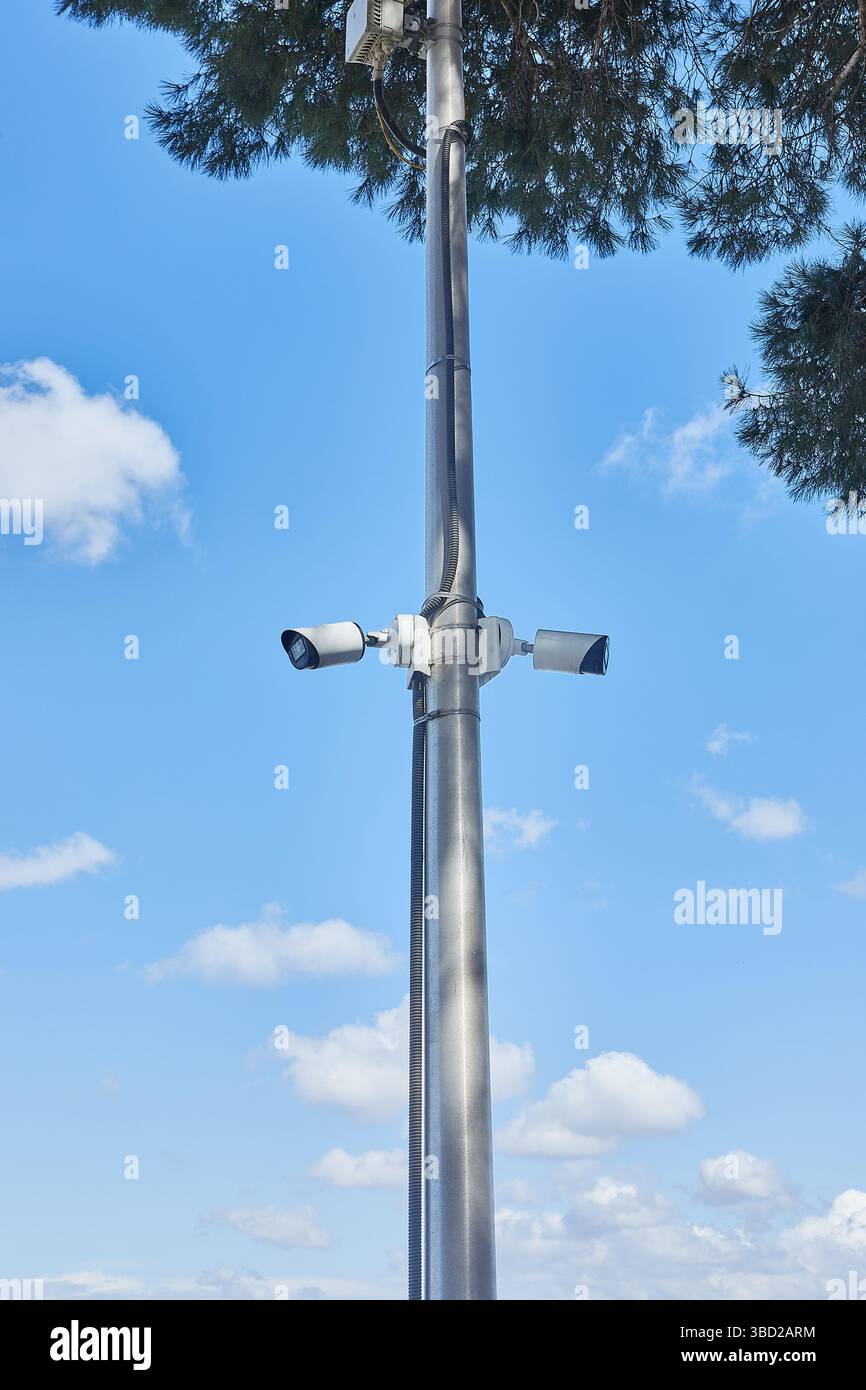 A security pole with mounted surveillance cameras under a clear blue ...