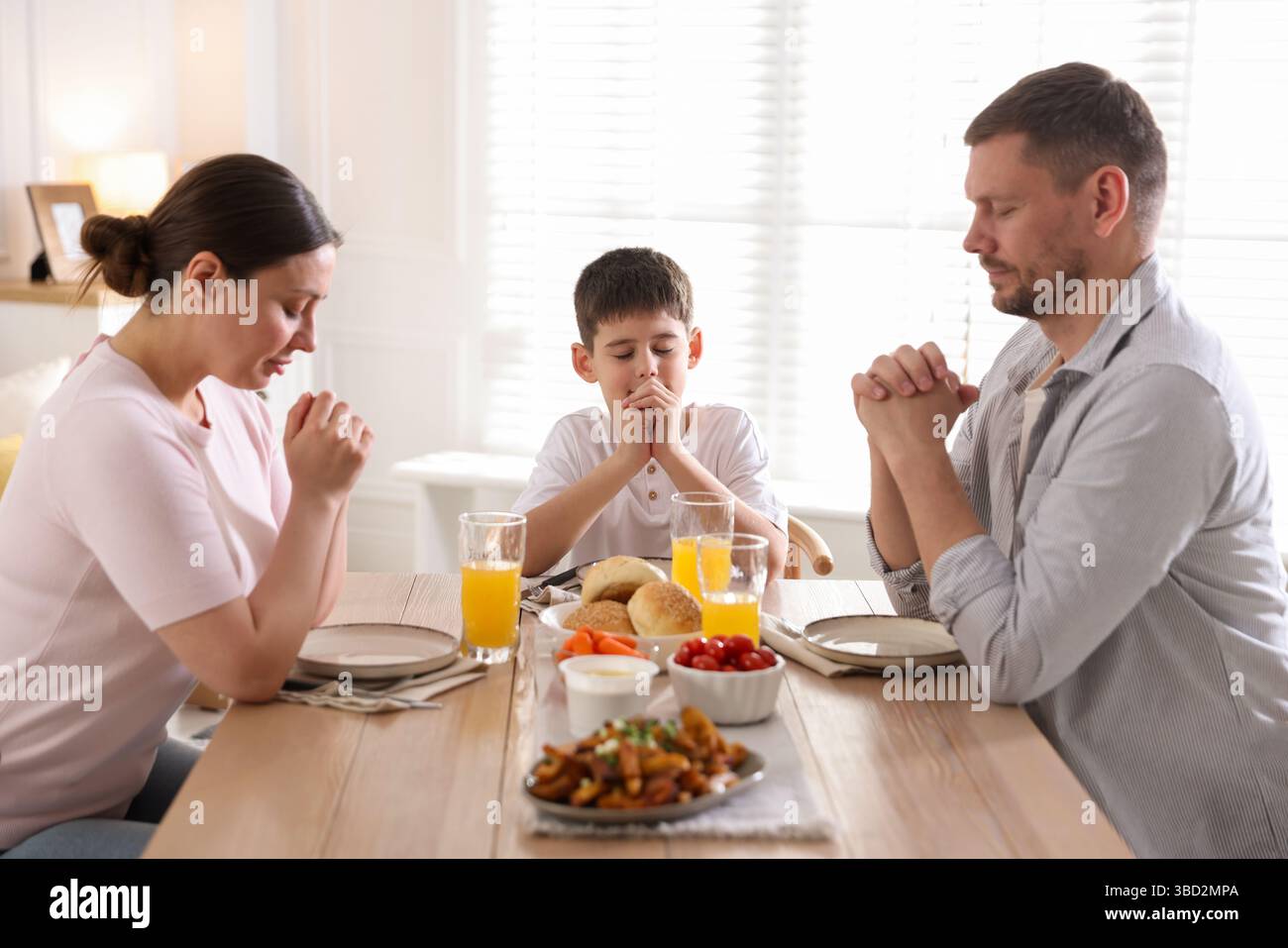 Family praying together before dinner at table indoors Stock Photo - Alamy