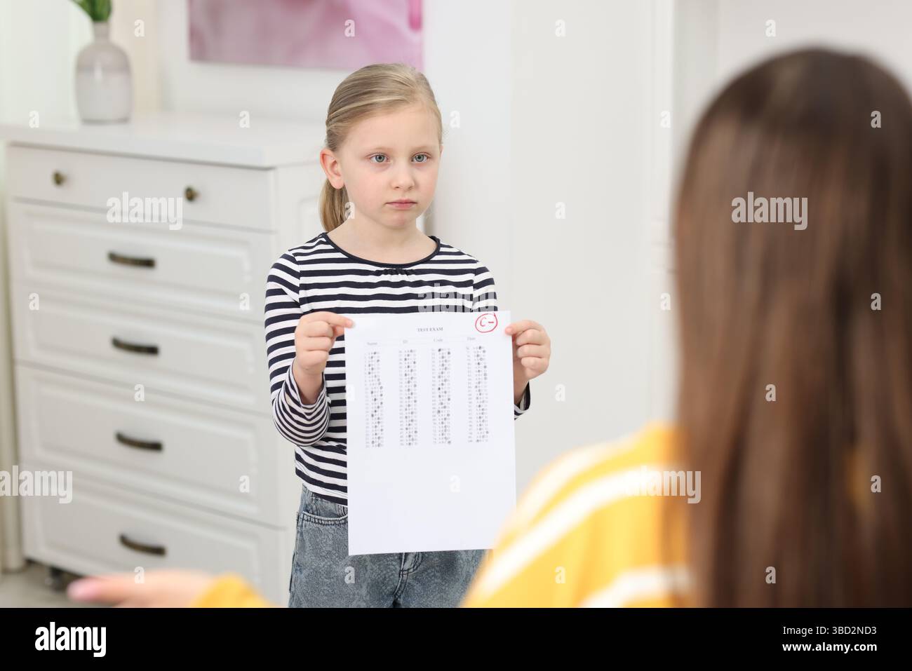 School grade. Sad girl showing answer sheet with bad mark to her mother ...