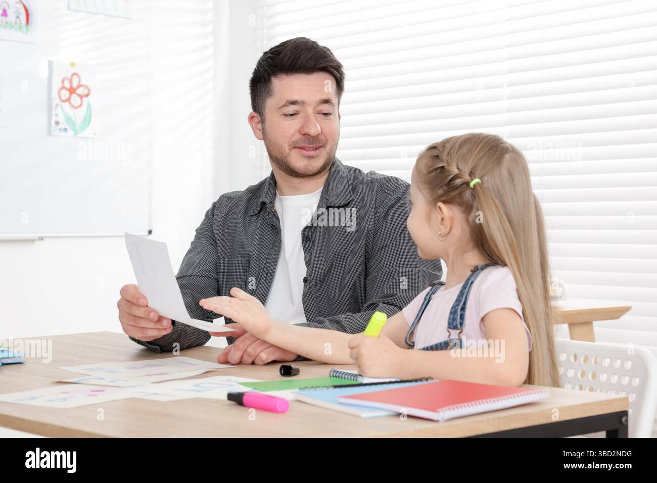 Teacher having lesson with little girl at desk indoors Stock Photo - Alamy
