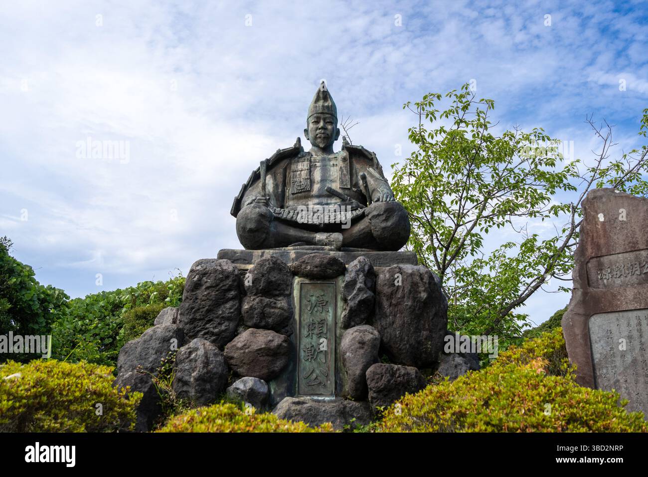 Bronze statue of shogun Minamoto no Yoritomo seated in armor on a stone ...