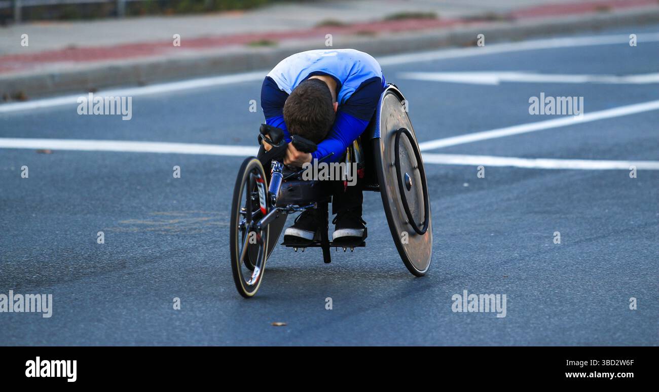 A determined athlete is racing in a wheelchair on an urban street ...