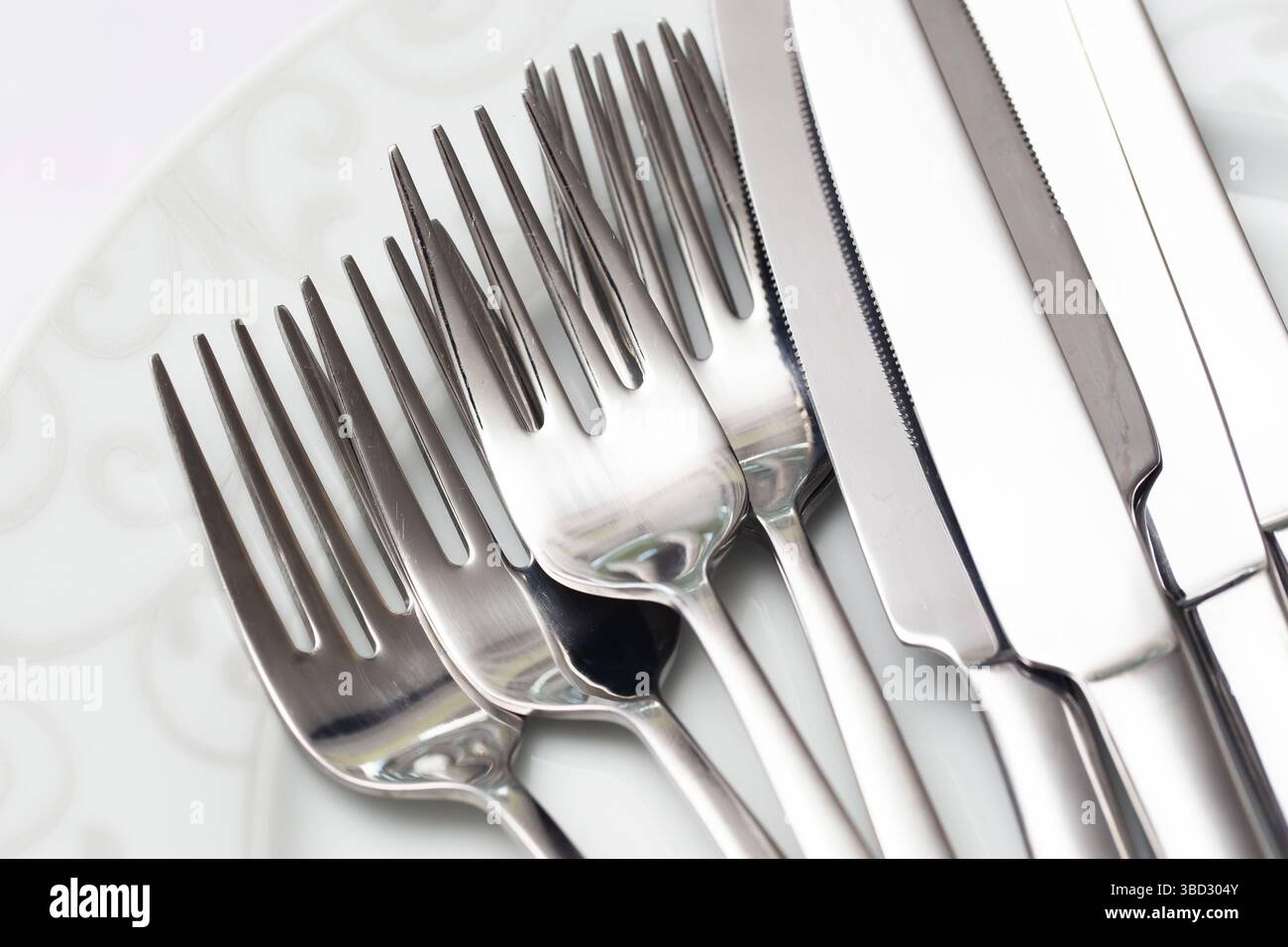 Stainless steel cutlery set. Forks and knives on elegant plate ...