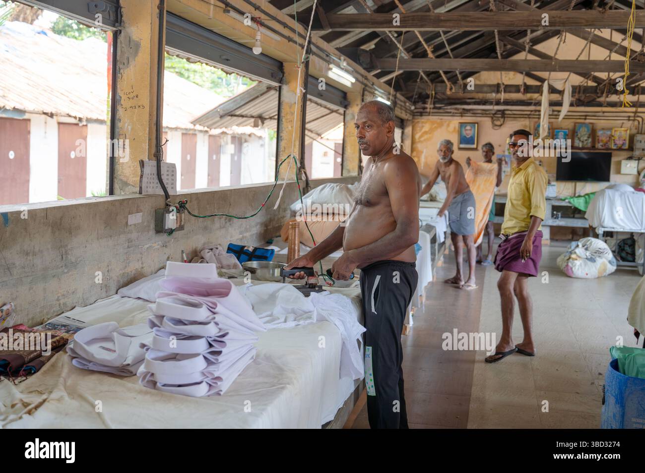 Man working with traditional indian electrical iron, Dhobi Ghat, open ...