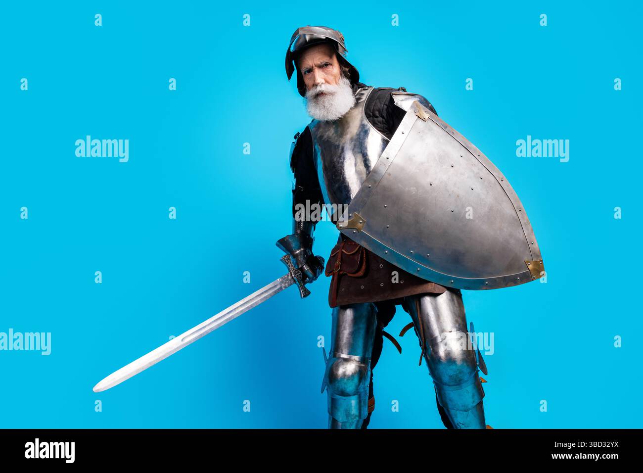 Mature knight in shining armor with shield and sword on a blue background portraying medieval ...