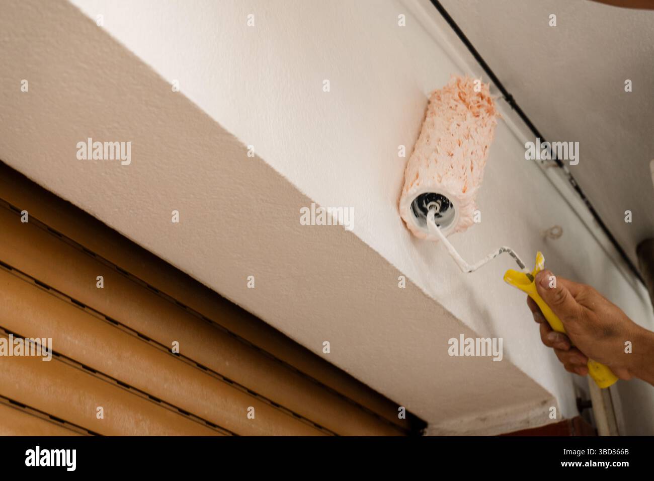 Painter using paint roller, painting facade of residential building ...