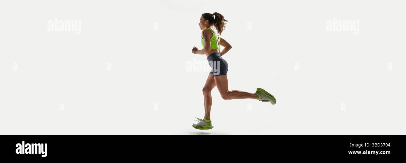 Tattooed female athlete caught mid-run with hair in motion and muscles ...