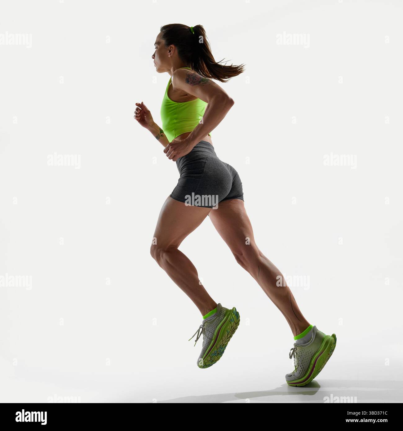 Female athlete sprinting with power and focus over white studio ...