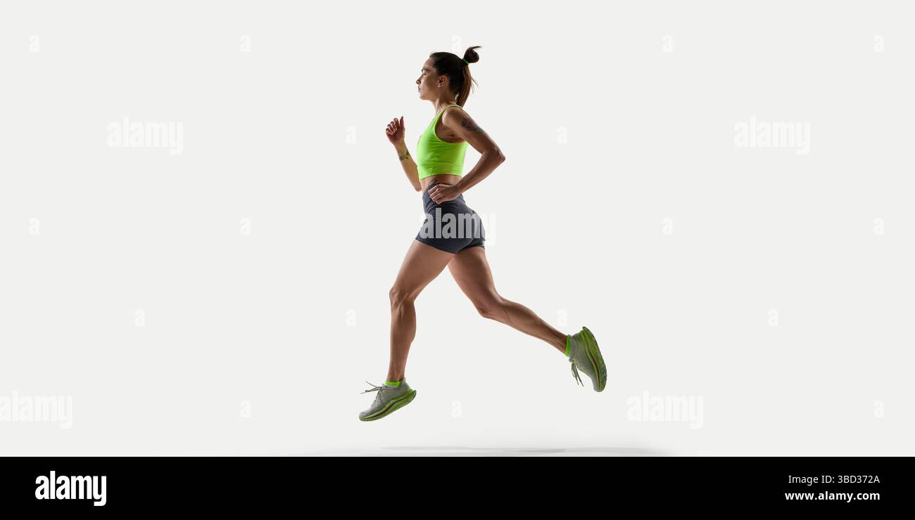 Low angle of woman in bright top captured mid-leap during running ...