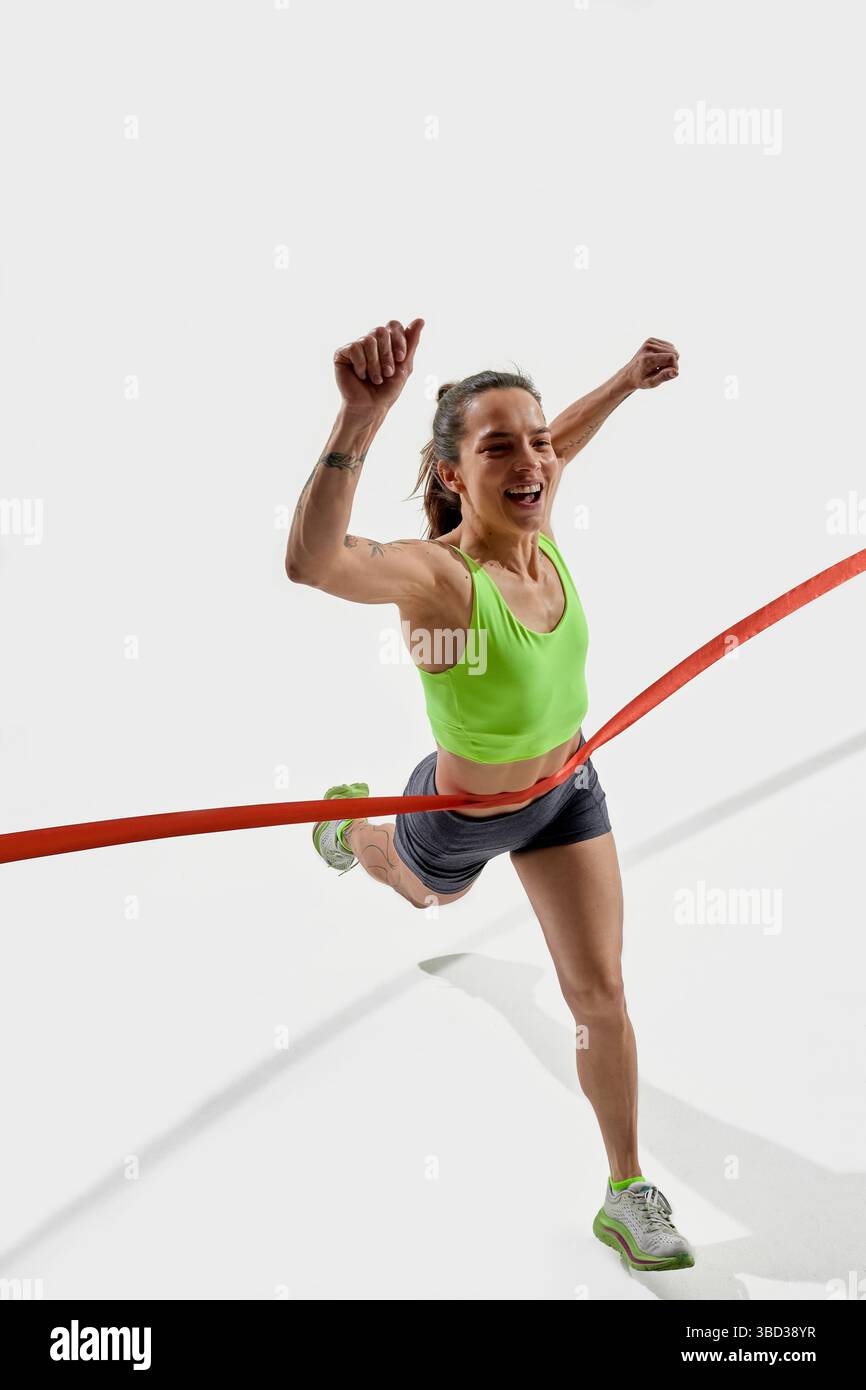 Happy female runner crosses finish line with fists up and smiling face ...