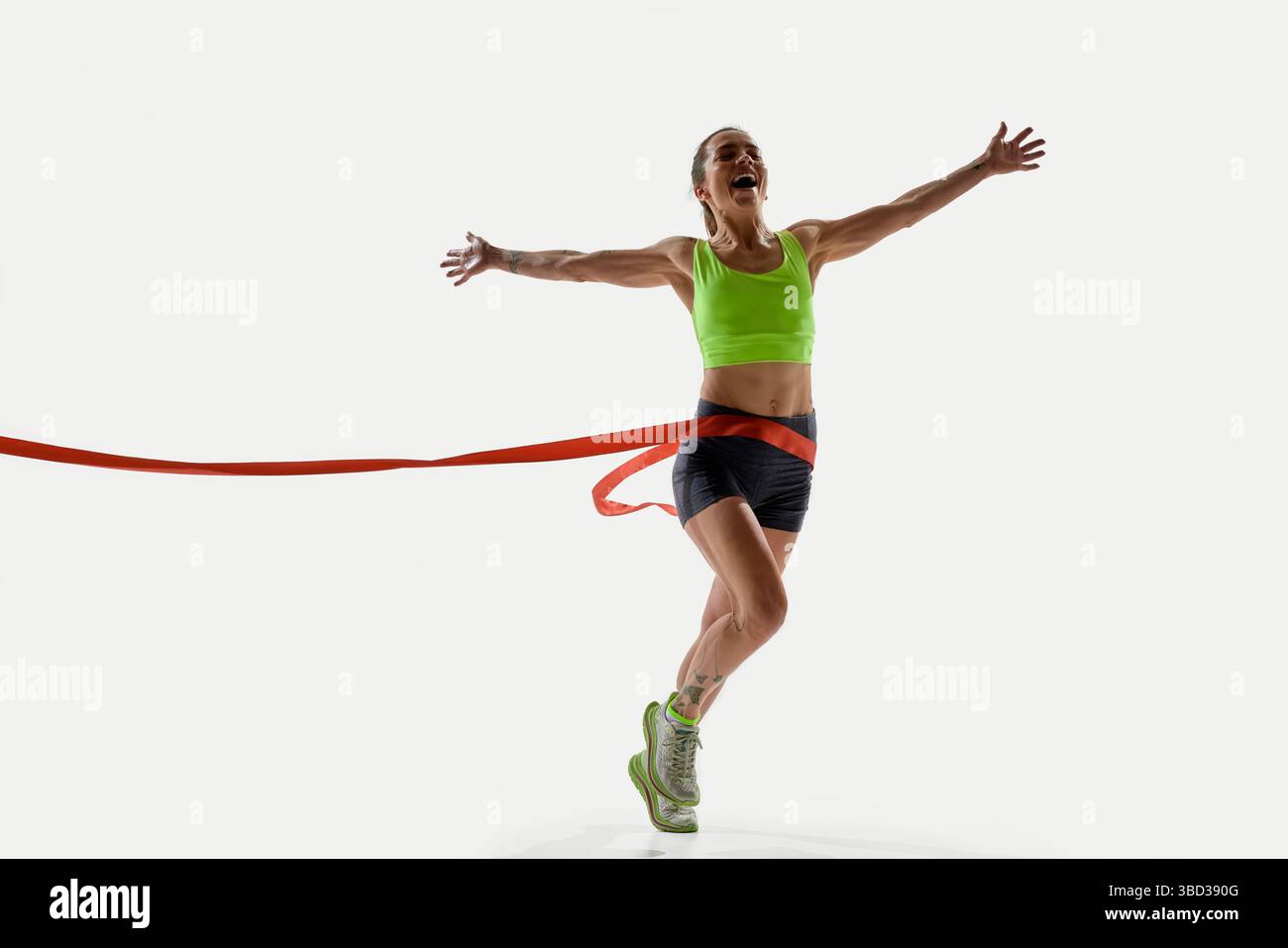Female athlete breaks finish line with open arms and joyful face in ...