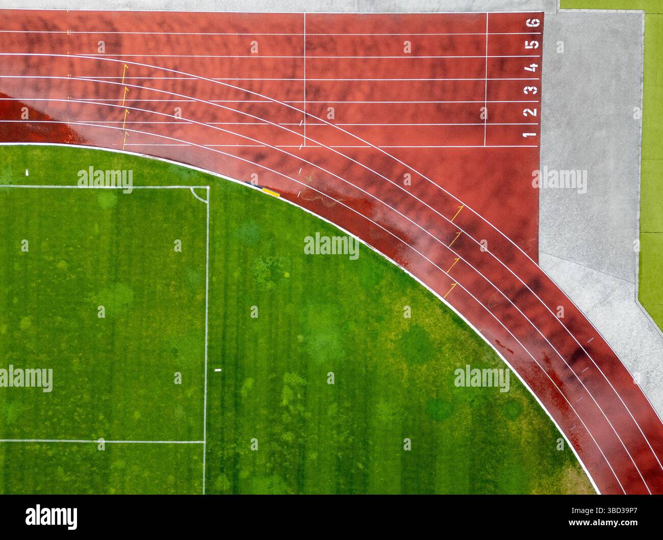 Aerial view of a red running track with marked lanes and curved lines ...