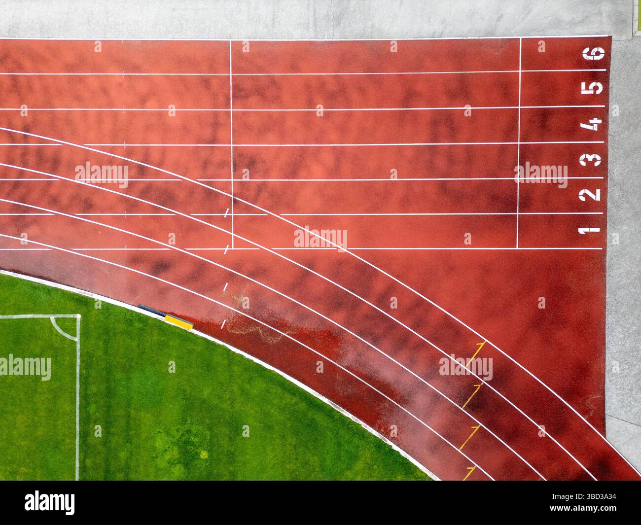 Aerial view of a red running track with marked lanes and curved lines ...