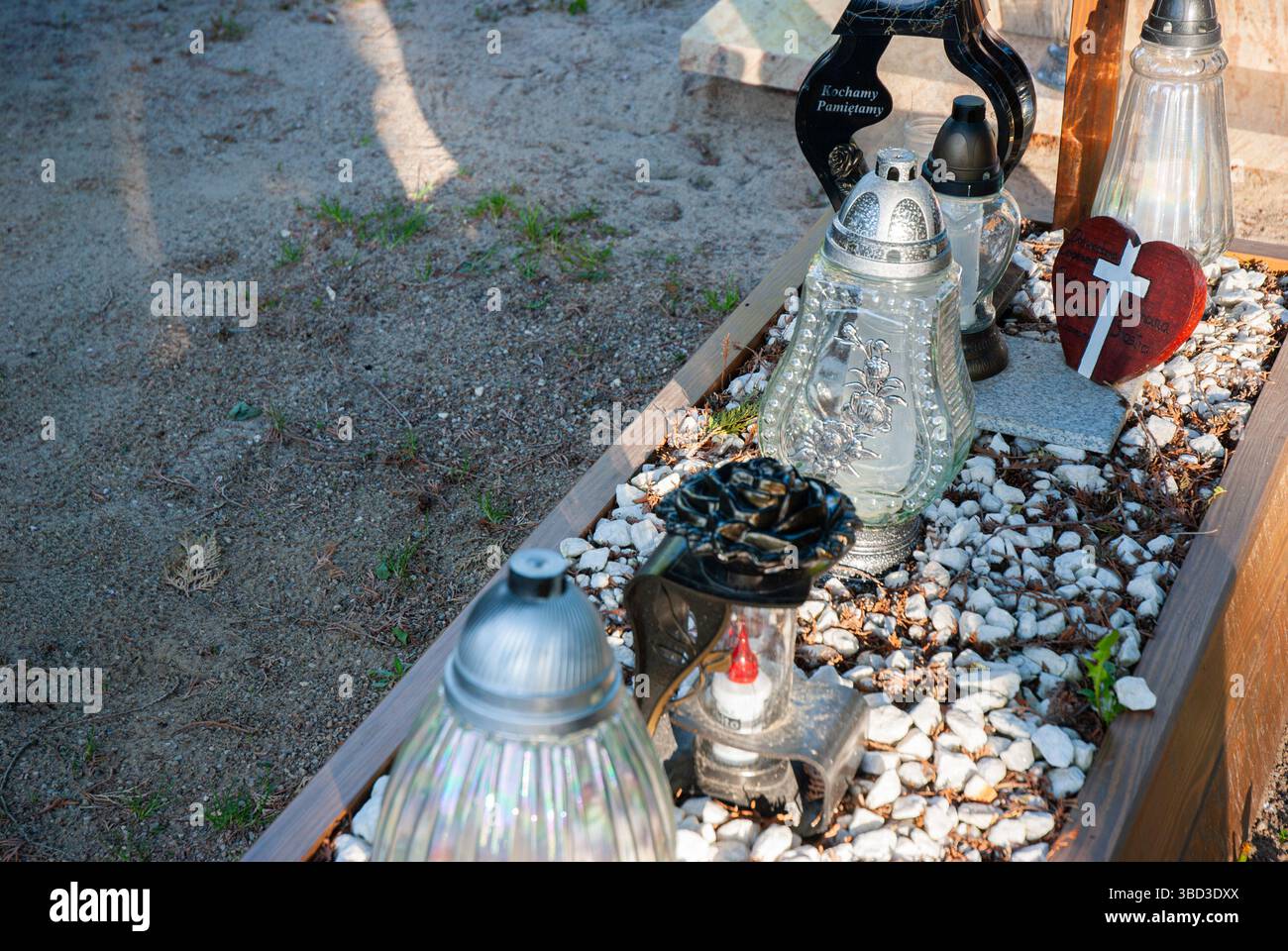 Memorial candles and heart-shaped symbol in cemetery on bright day with ...