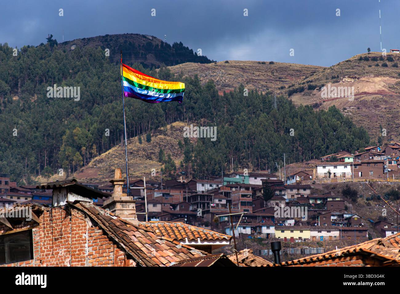 Colorful flag of Cusco, Peru, fluttering over the reddish rooftops of ...