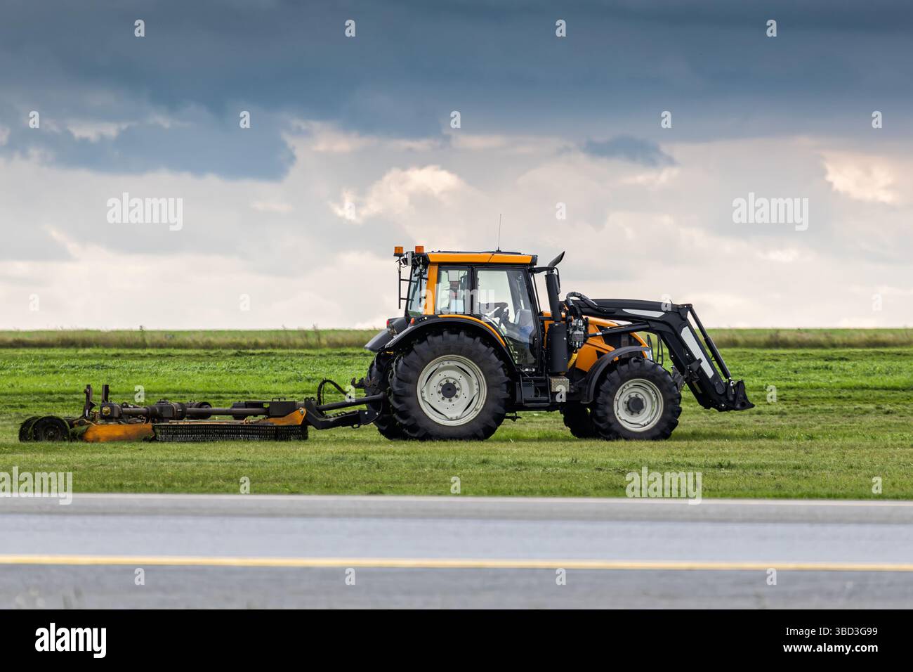 Wheel tractor with lawn mower working by the road Stock Photo - Alamy