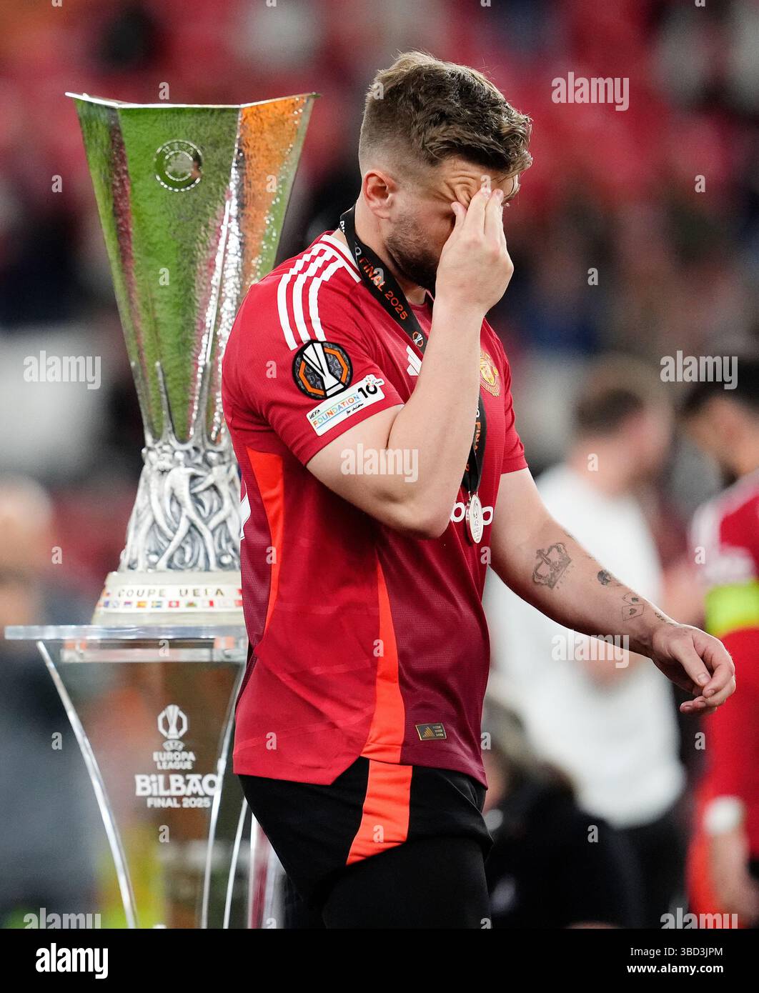 Manchester United's Luke Shaw reacts as he walks past the trophy after ...