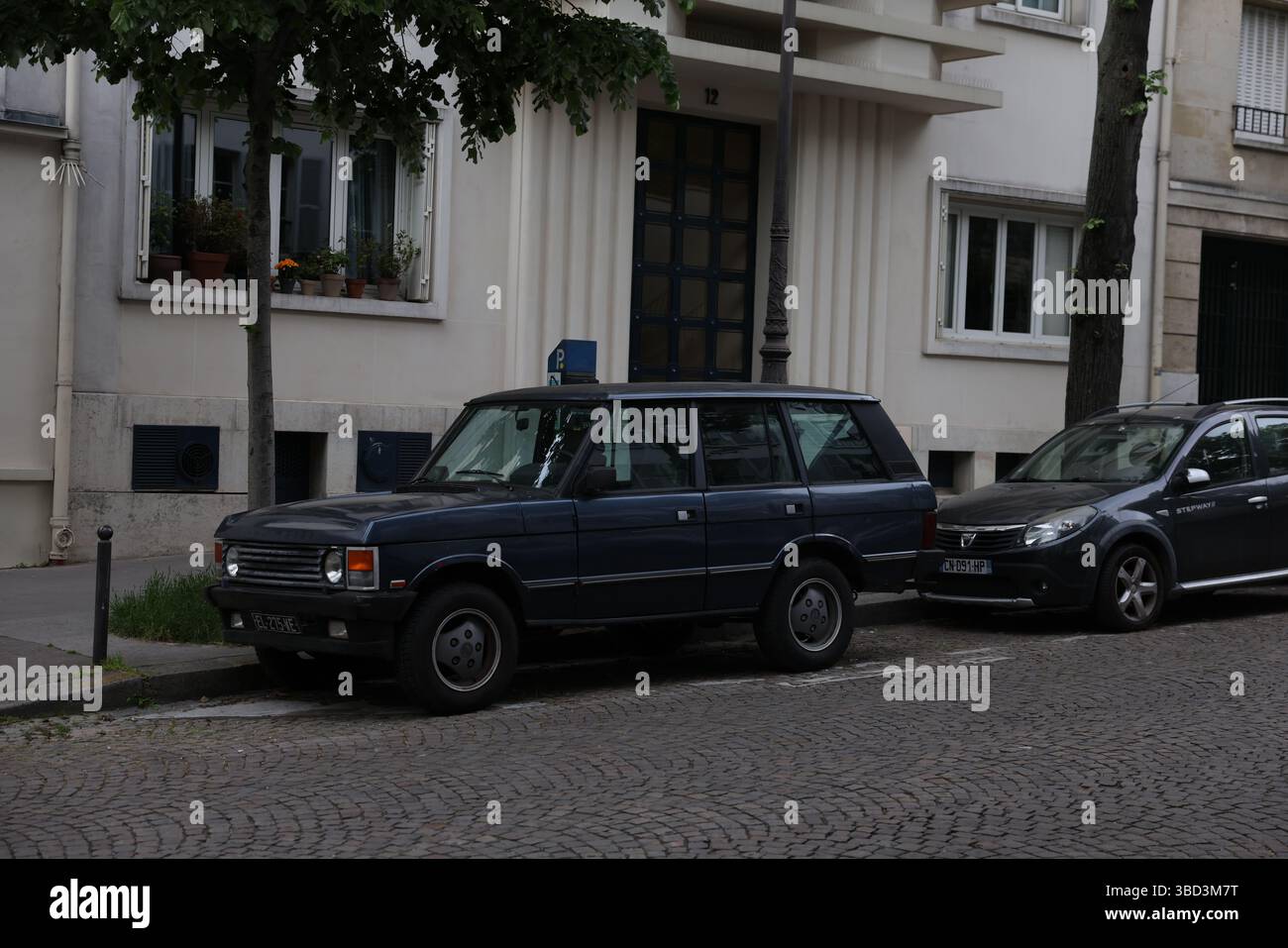 Two cars—a dark blue Range Rover and a dark gray Renault—are parked on ...