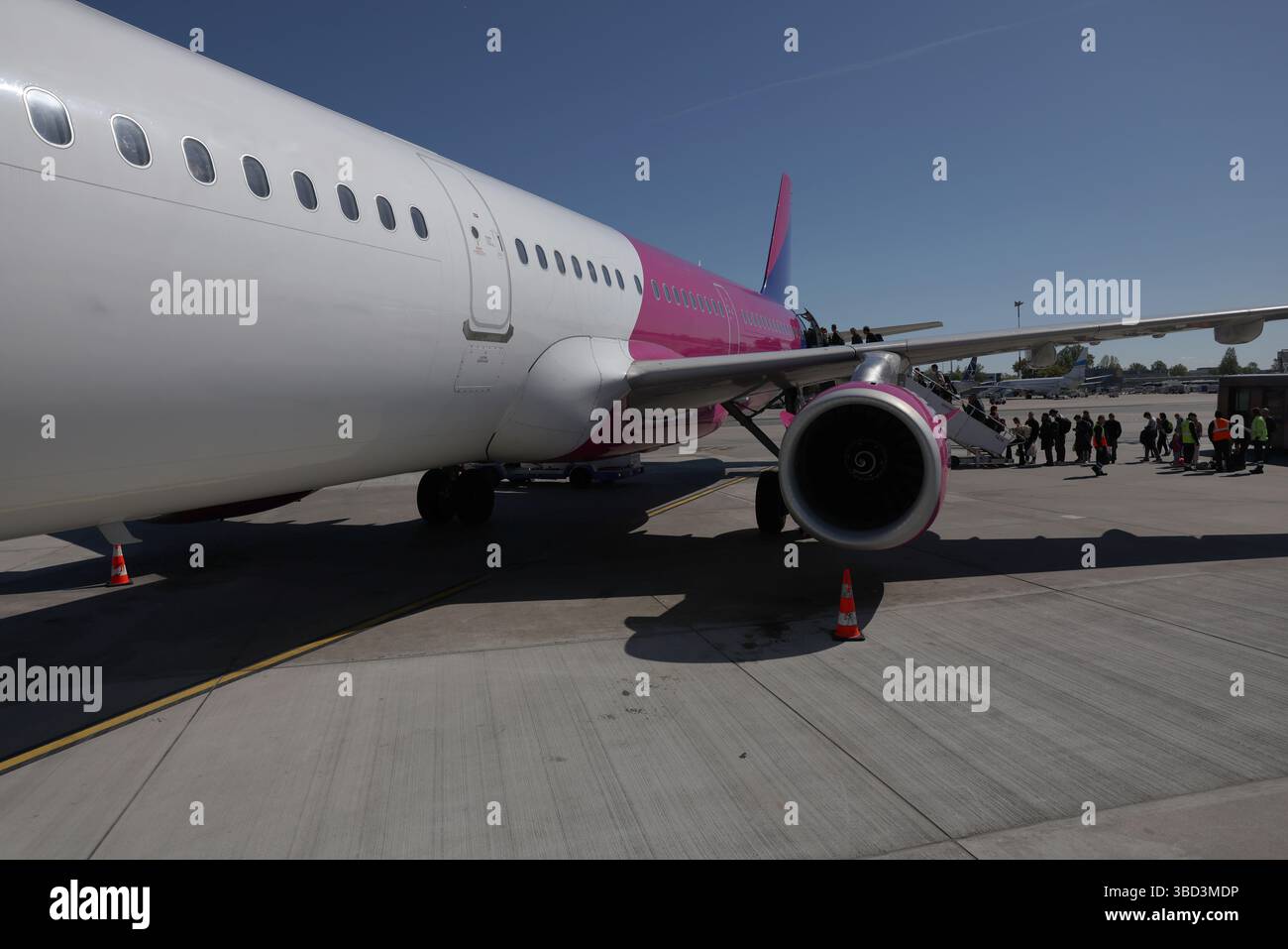 A commercial airplane with a striking red tail sits on a runway, ready ...