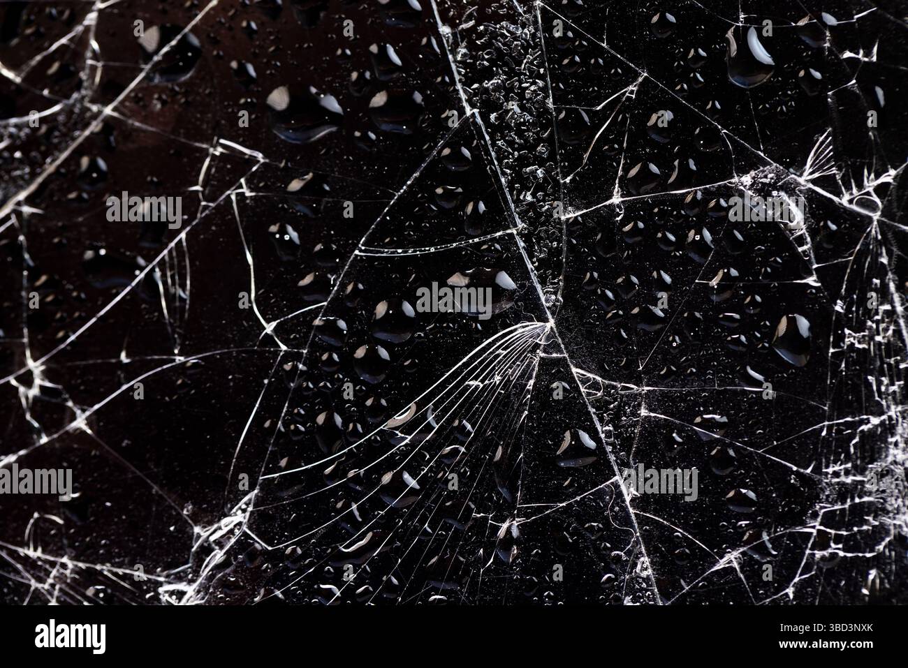 water covered broken glass with a lot of damage on a black background ...
