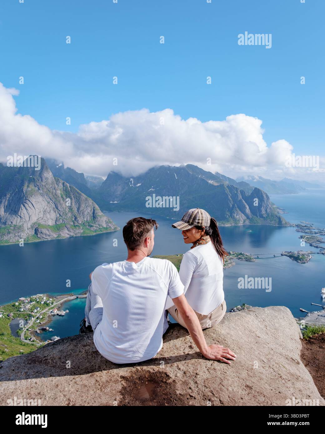A couple sits atop a rocky ledge, gazing at the stunning landscape of ...