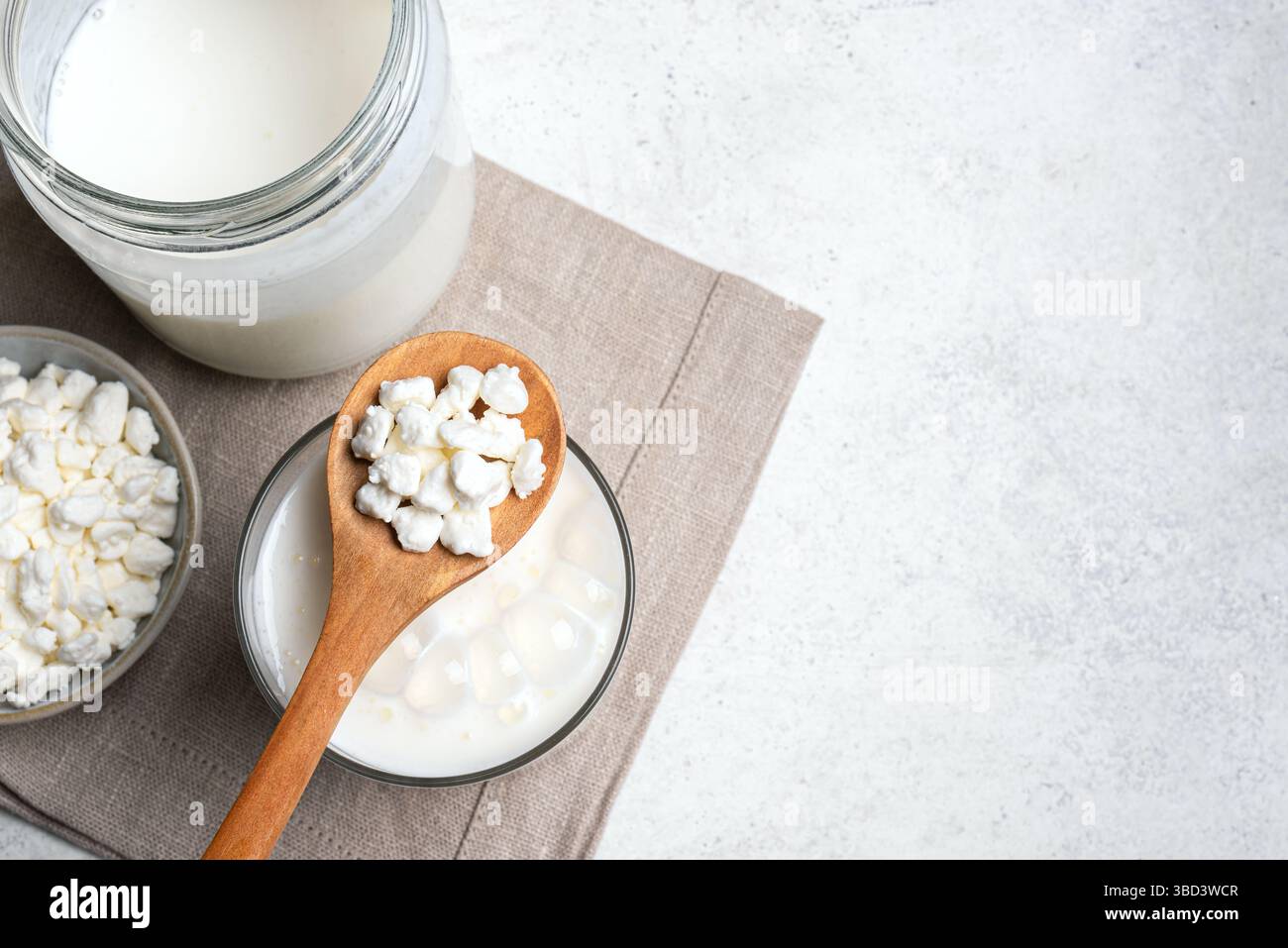 Milk kefir grains on wooden spoon and glass of kefir, white background ...