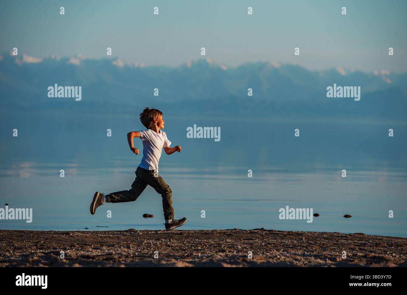 Boy running along the lake shore Stock Photo - Alamy