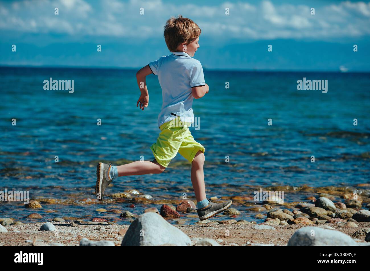 Boy running on lake shore at sunny day Stock Photo - Alamy
