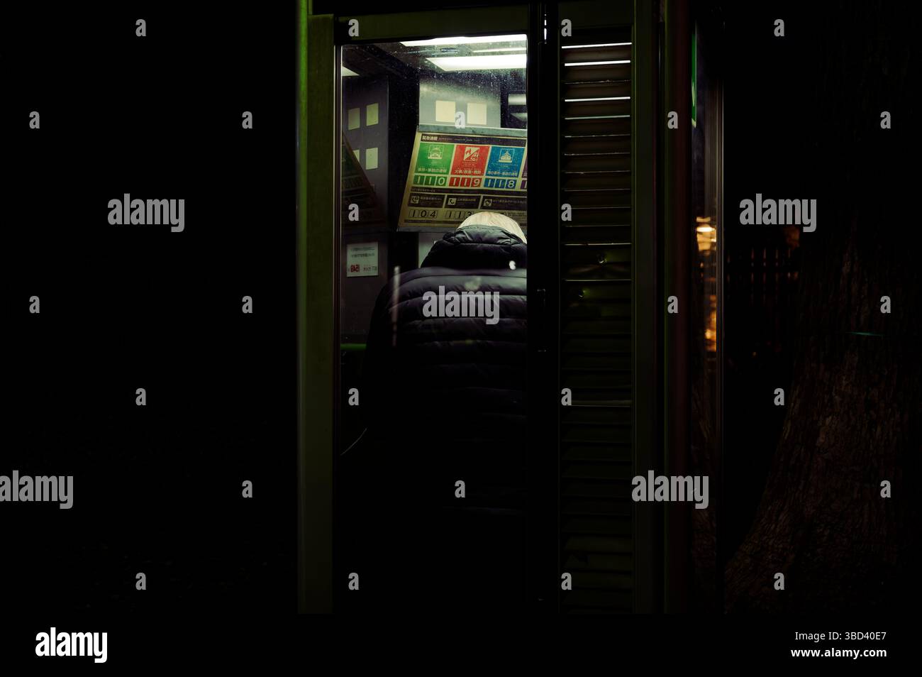 A solitary figure in a dark coat leans over the receiver in a dimly lit ...