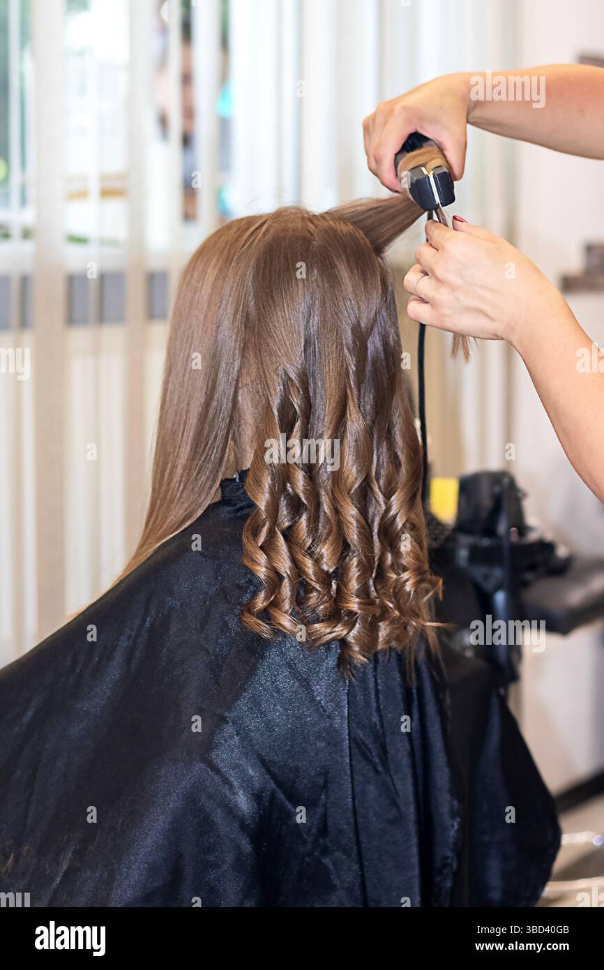Stylist creating curls for a client at a professional hair salon Stock ...