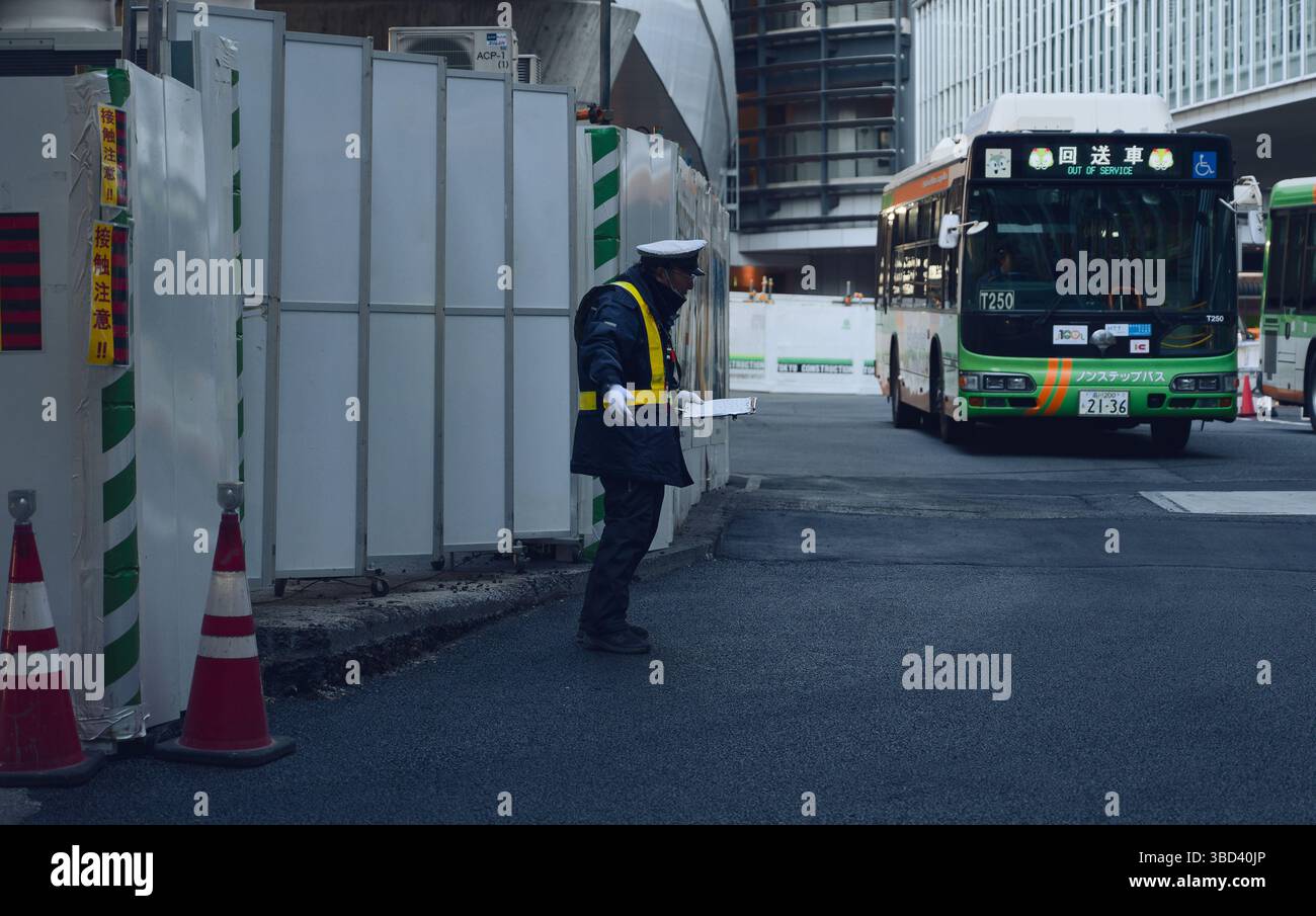 Traffic officer guides bus operations, clipboard in hand, as a city bus ...