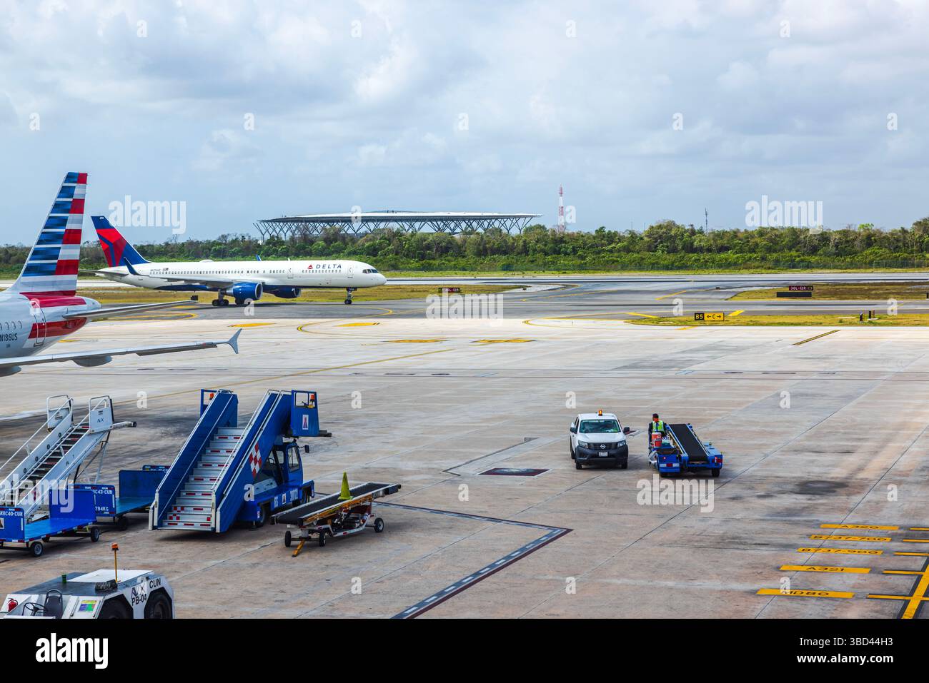 Delta aircraft taxiing at airport with ground service vehicles and jet ...