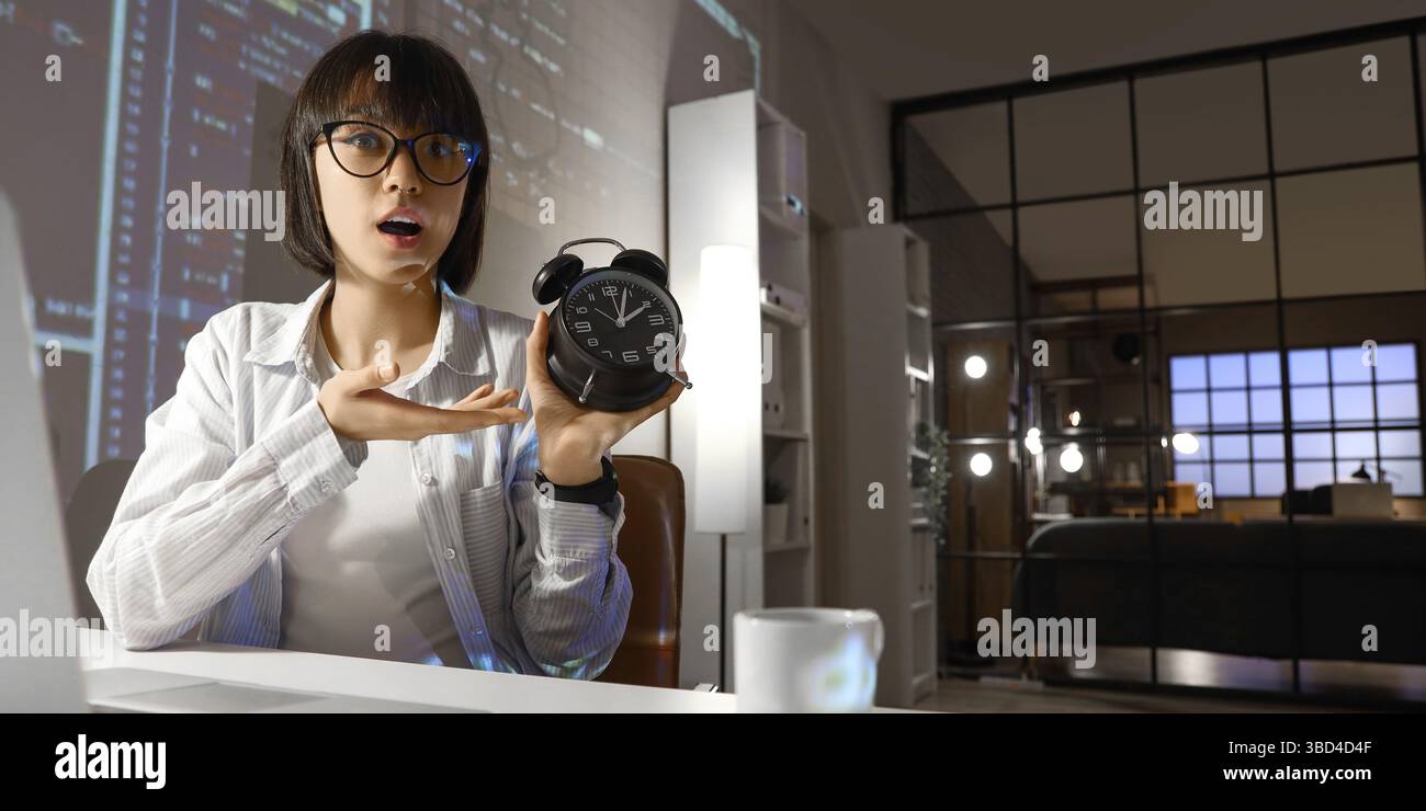 Shocked female programmer with alarm clock in office at night Stock ...