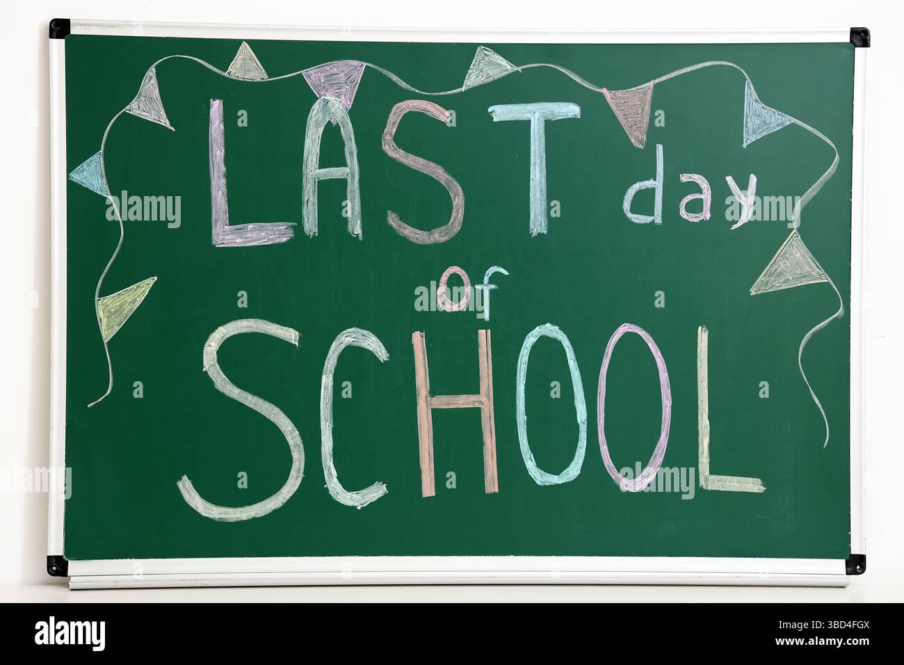 Blackboard with text LAST DAY OF SCHOOL and drawn flags on light wall ...
