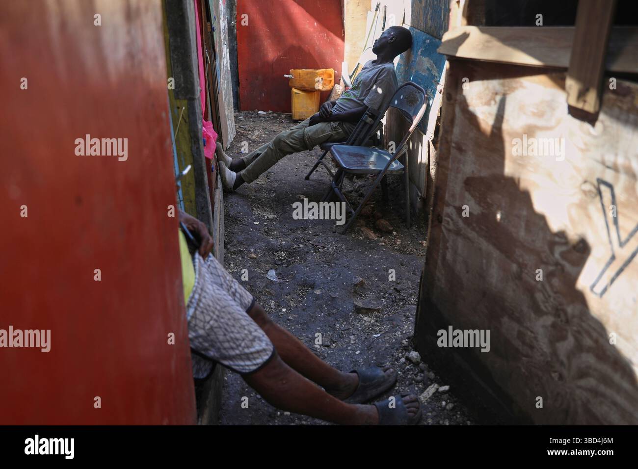A man leans back on a chair to rest, in a shelter for families ...