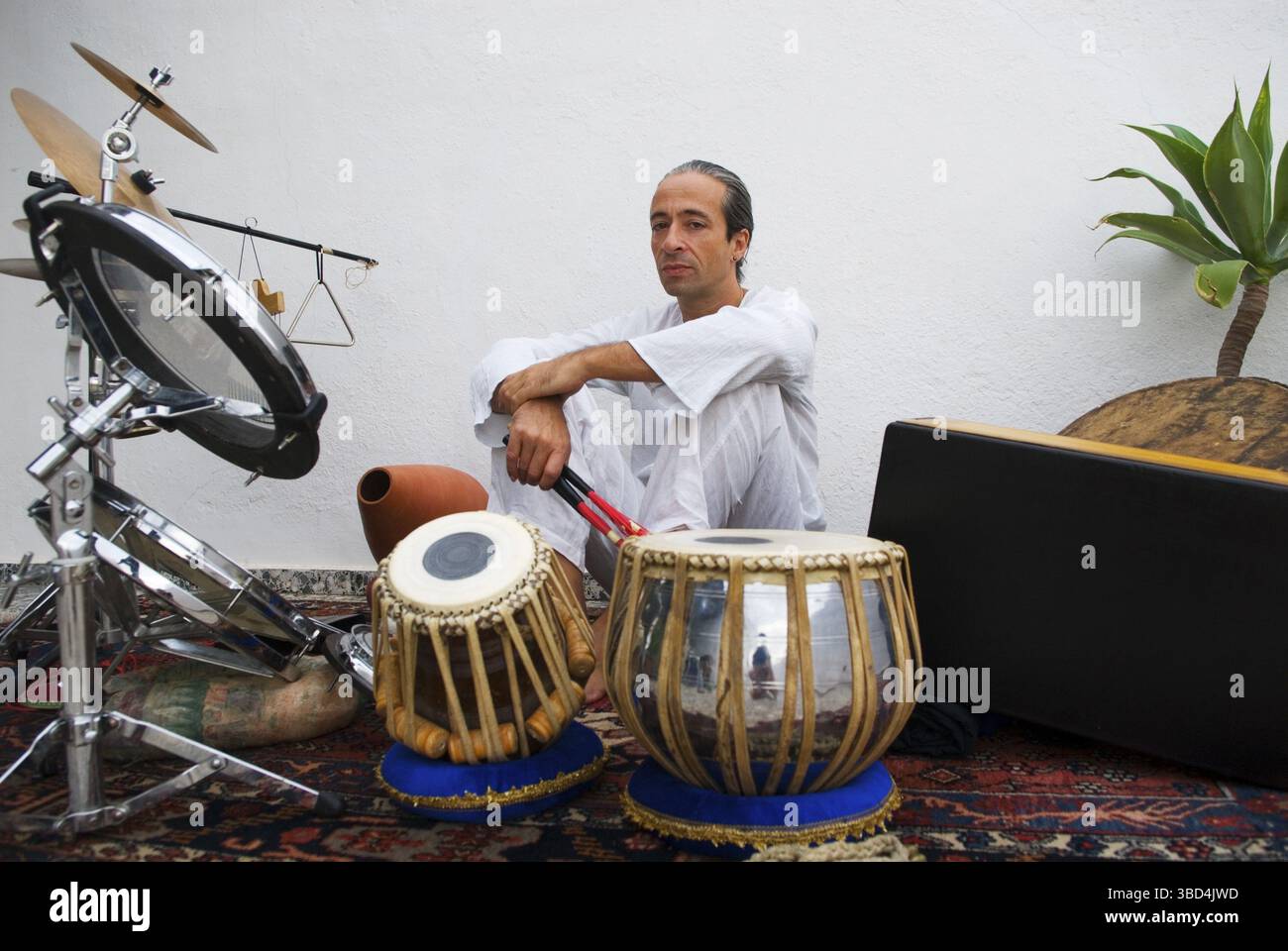 Musician in his early 40's, sitting amongst his percussion instruments ...
