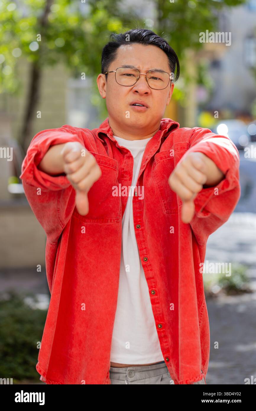 Dislike. Upset Asian middle-aged man showing thumbs down sign gesture ...