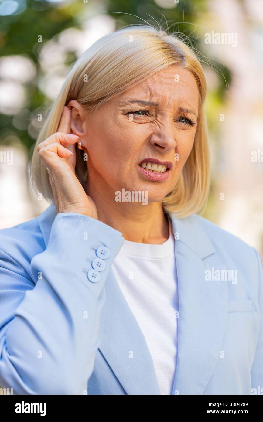 Earache. Sick mature businesswoman in formal suit suffers from ear pain ...