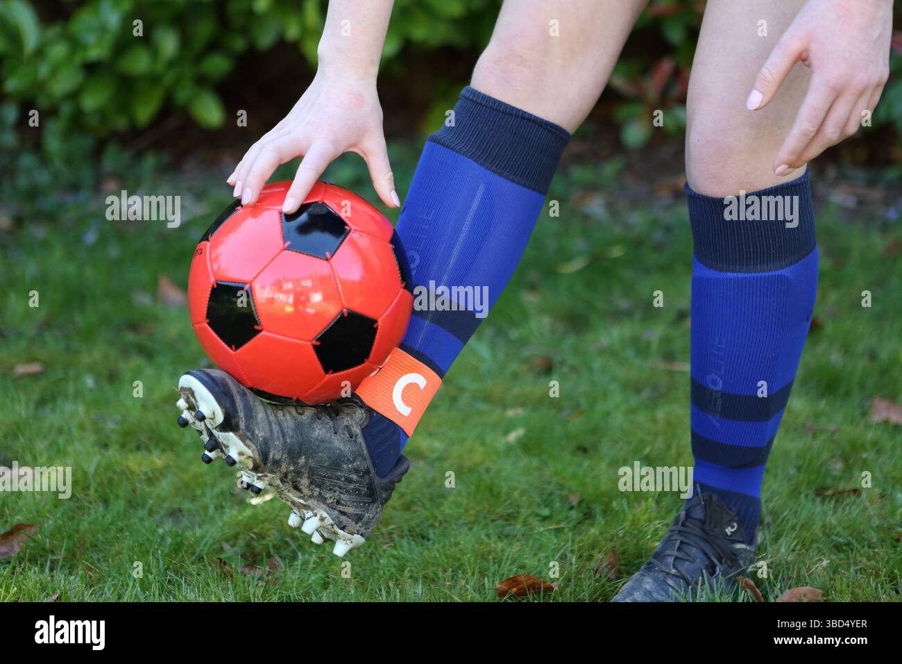 Female footballer balances football on boot with hand holding ball ...