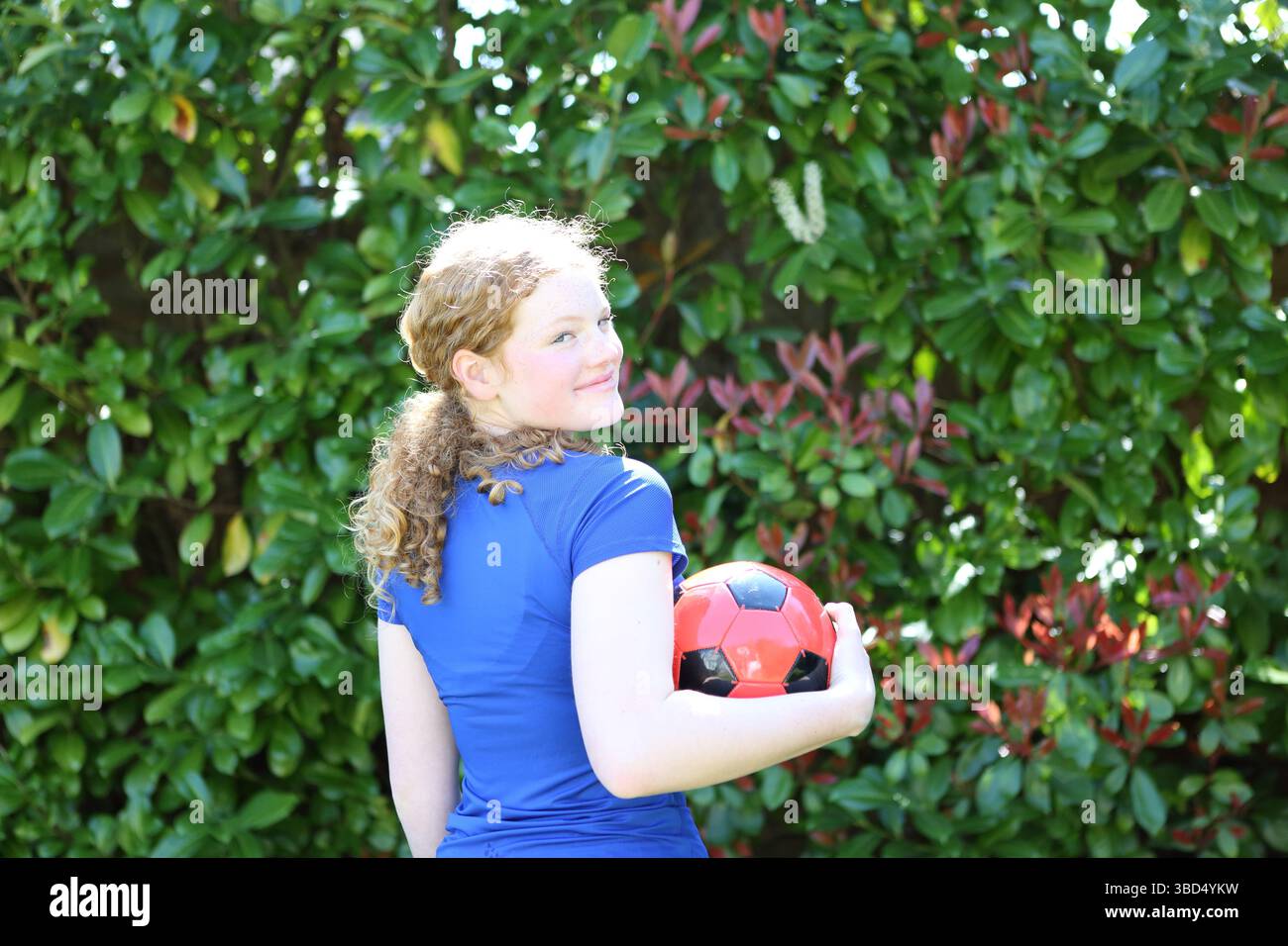 Girl holds football rear view over shoulder blue shirt footballer ...