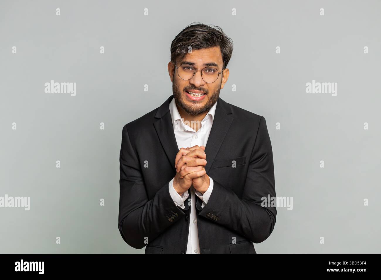 Please, God help. Indian businessman praying, looking at camera and ...