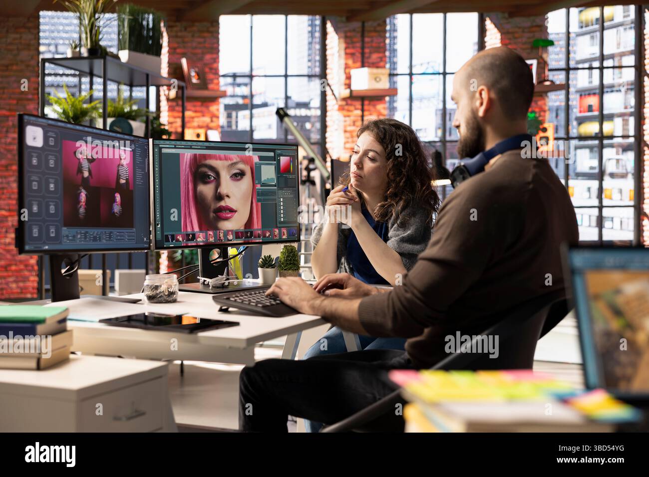 Graphic designer and photographer collaborate in a modern studio, using ...