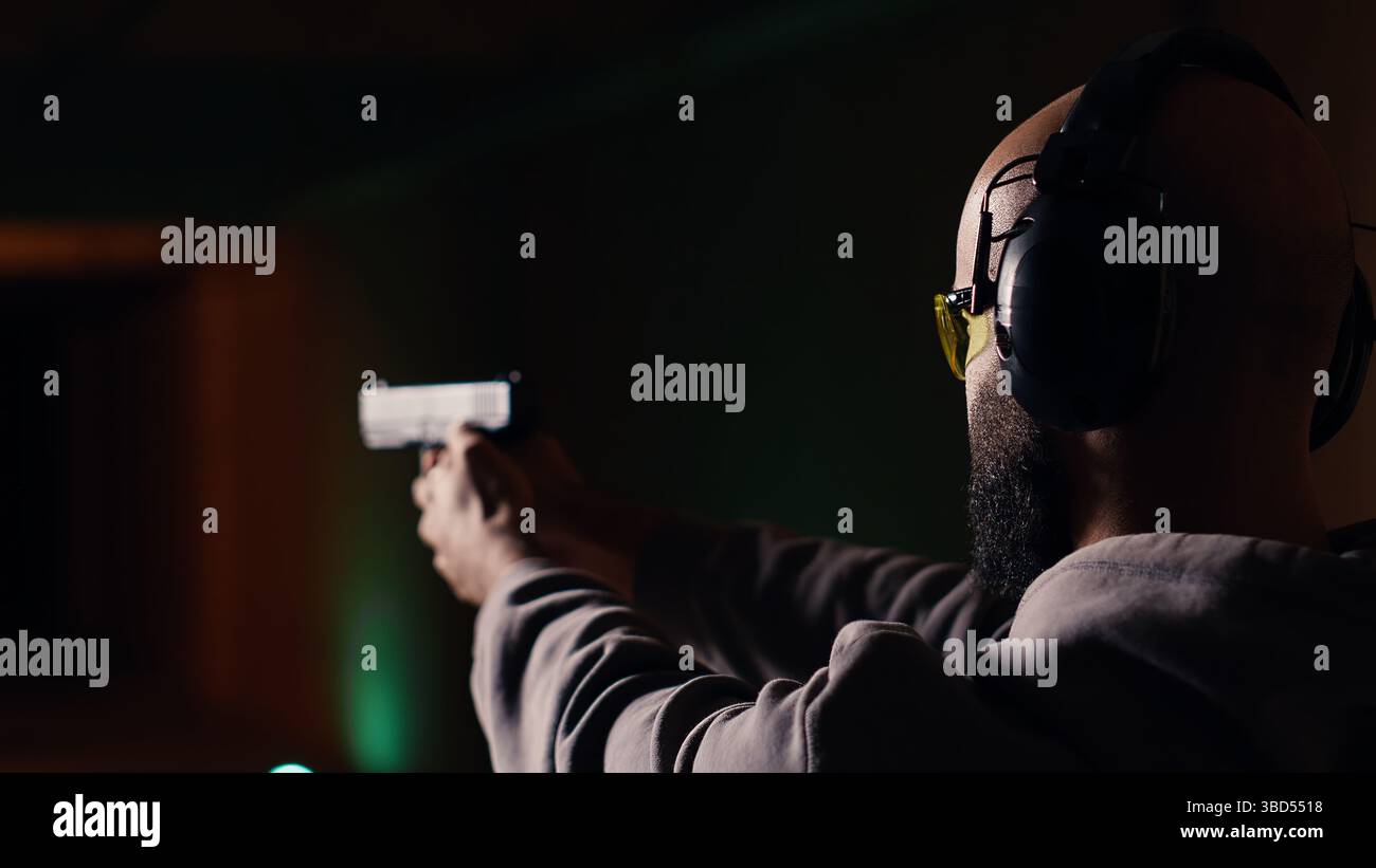 Shooting range customer shooting targets with pistol, learning to ...