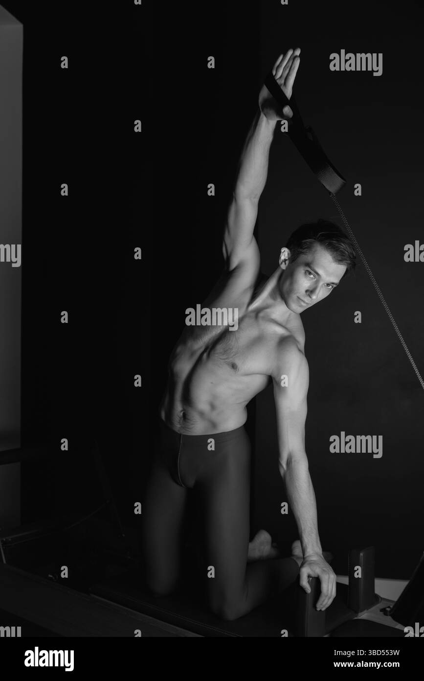 Slim male ballet dancer trains on Pilates equipment. Elegant pose, core ...