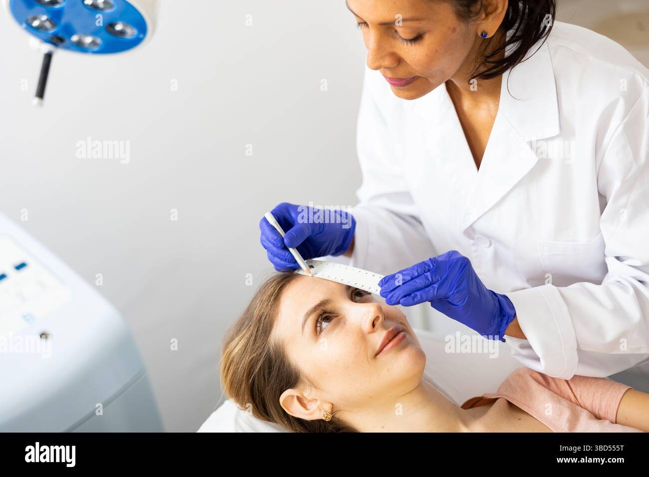 Beautician drawing correction lines on woman face Stock Photo - Alamy