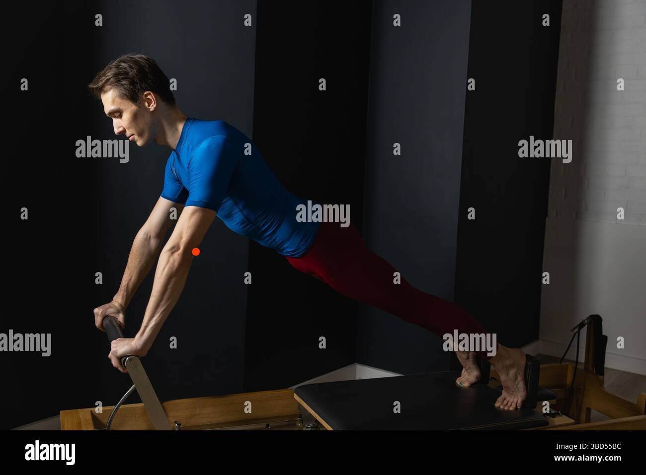 Slim male ballet dancer trains on Pilates equipment. Elegant pose, core ...