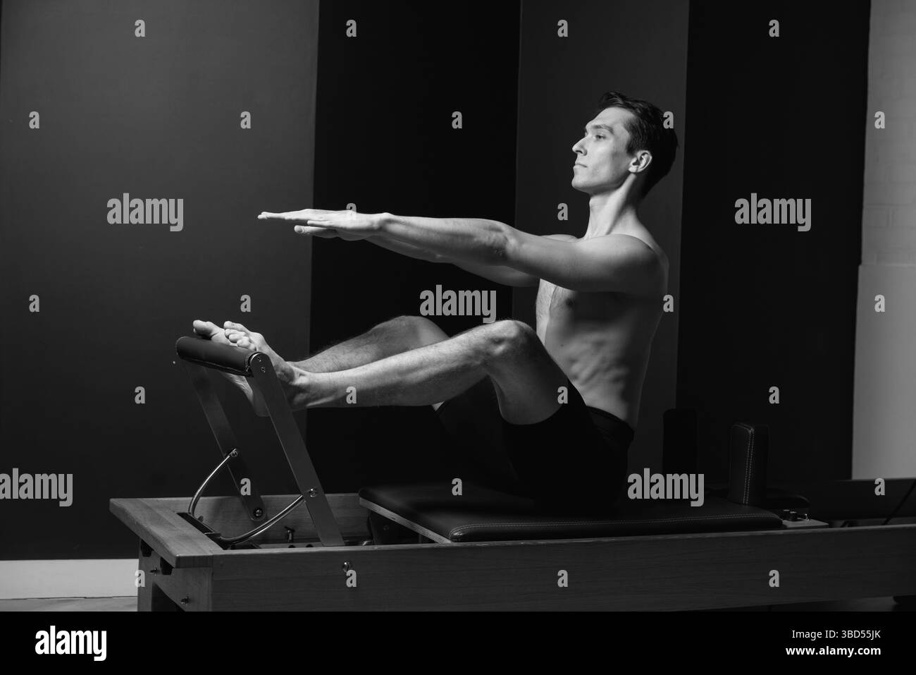 Slim male ballet dancer trains on Pilates equipment. Elegant pose, core ...
